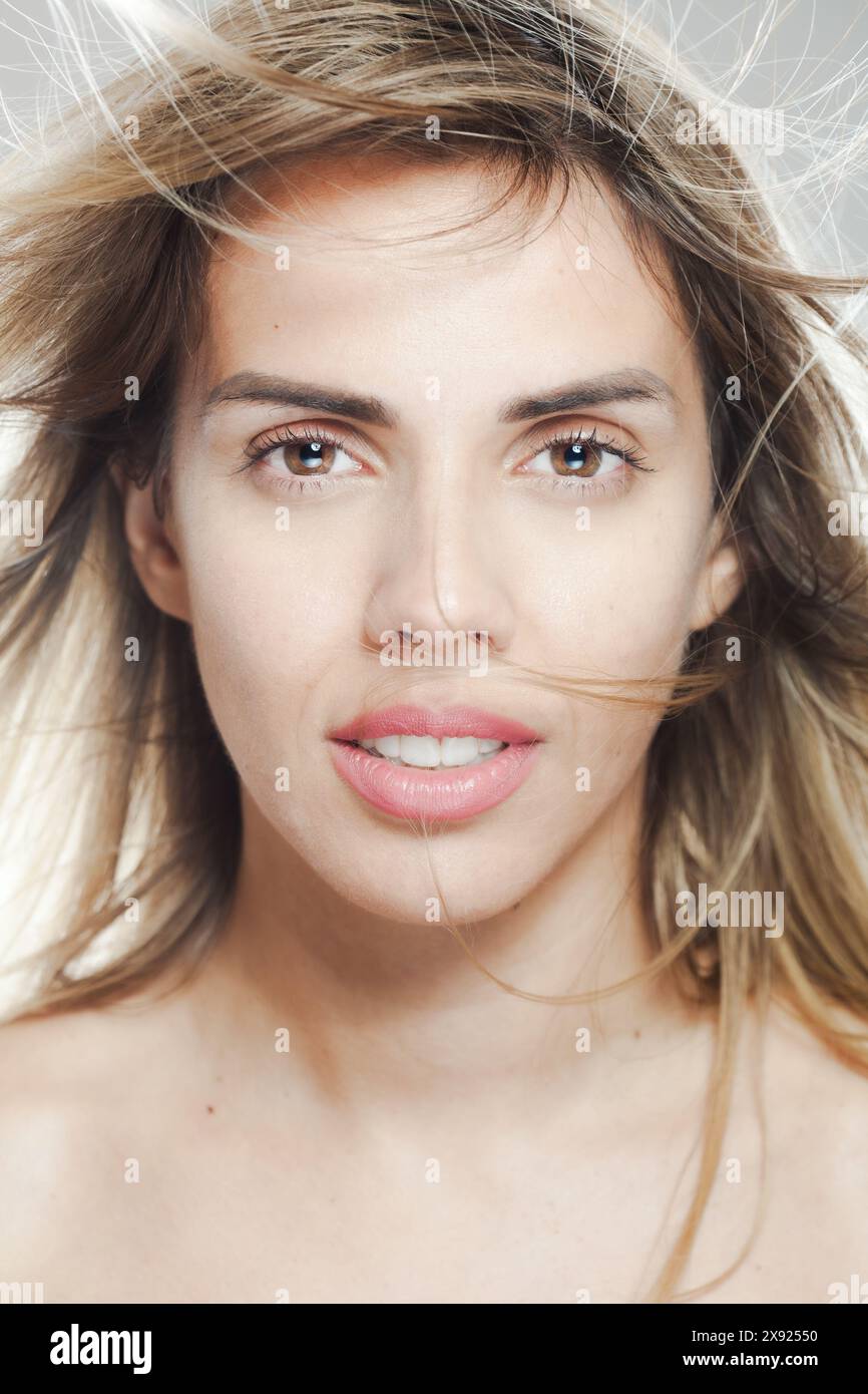 This image captures a close-up of a young woman featuring wind-blown ...