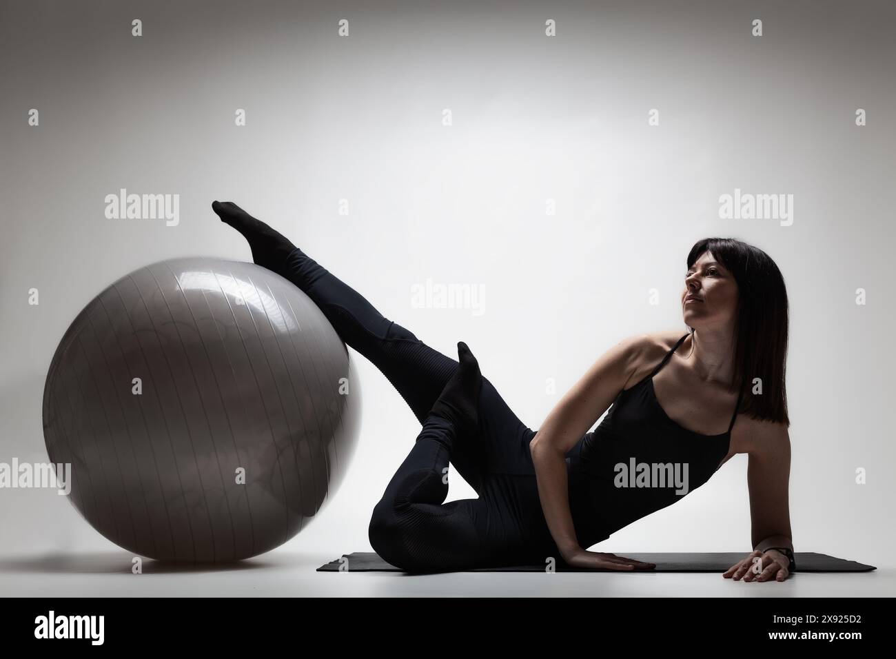 This image captures a young woman engaging in a Pilates workout using a ...
