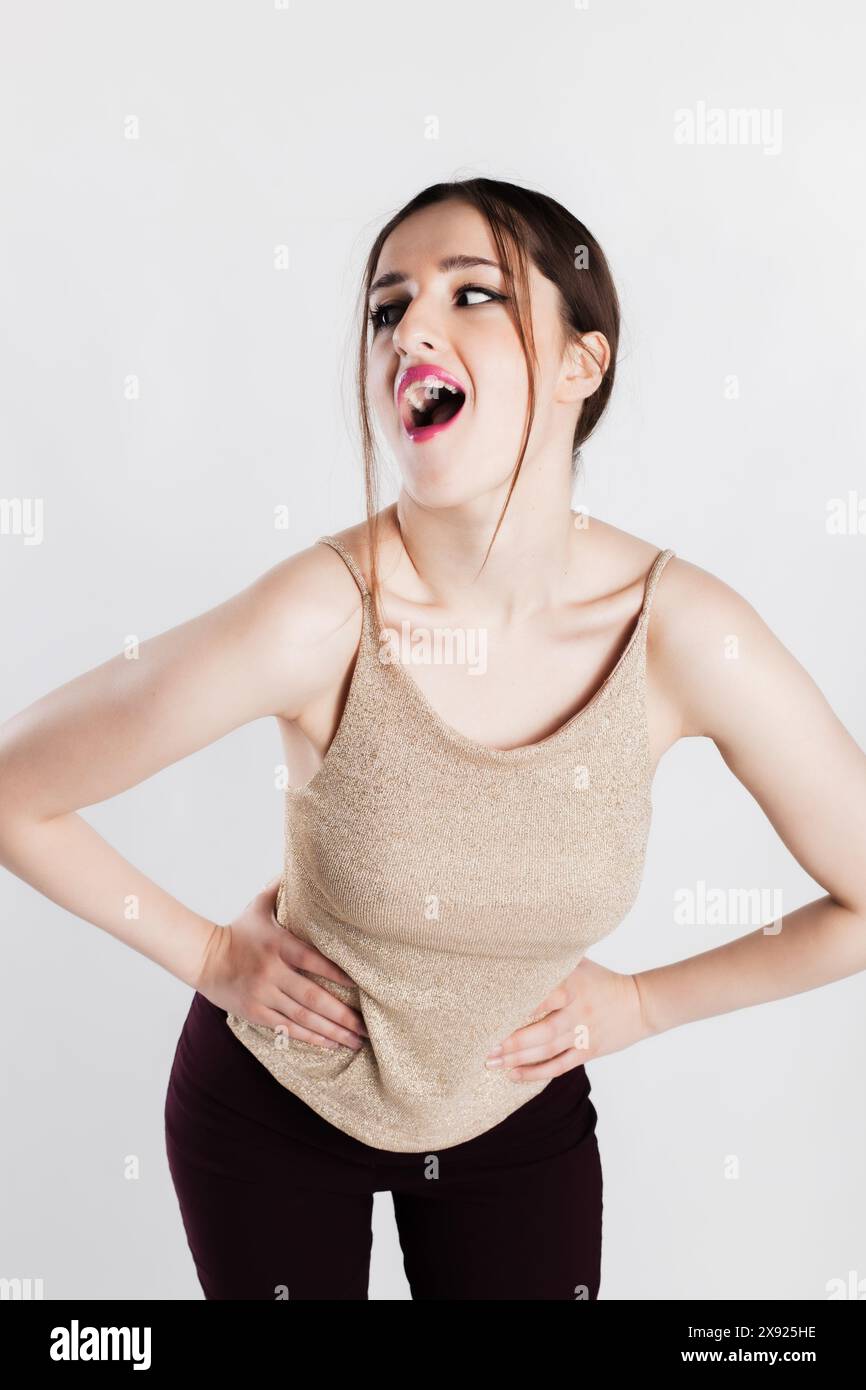 An exuberant young woman in a glittery tank top laughing heartily ...