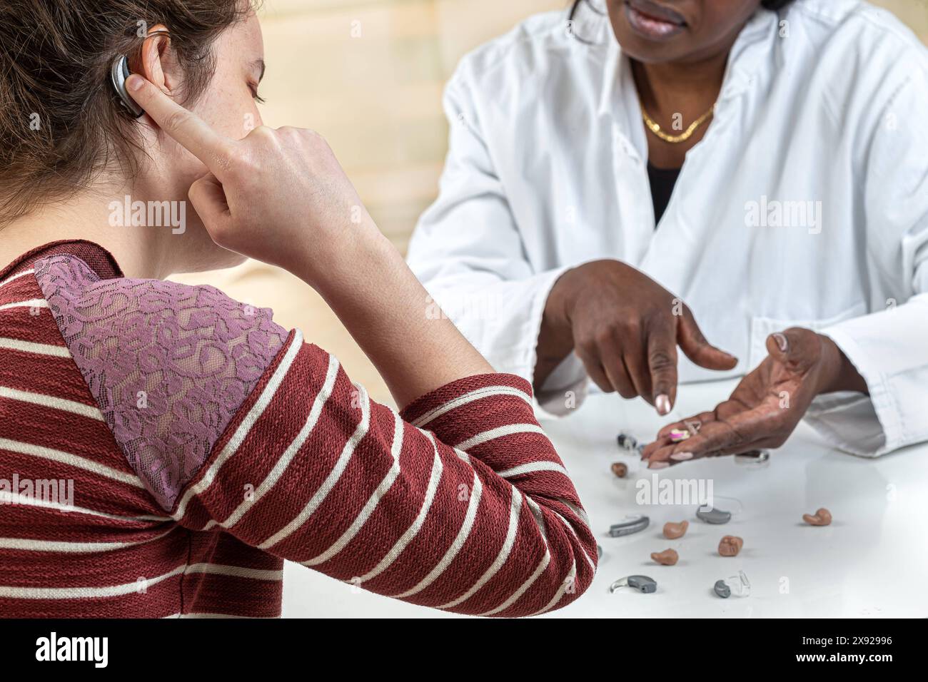 Patient trying different types of hearing aids. chatting with his ...
