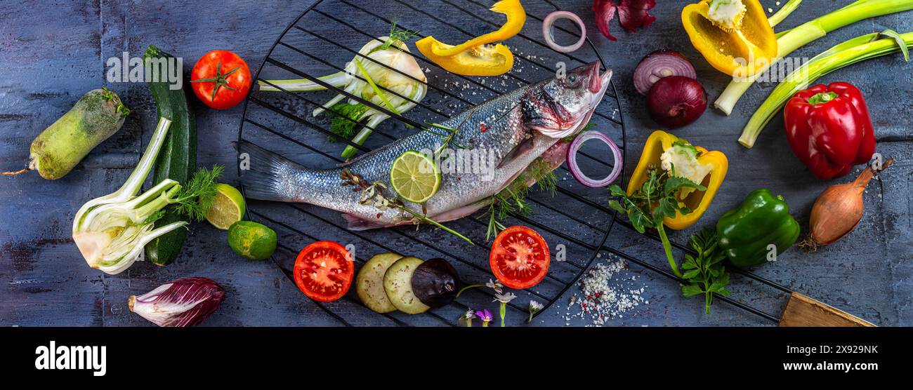 Pan of a sea bass on a barbecue grill, surrounded by vegetables ...