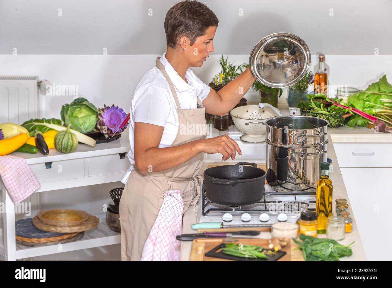 Young woman lifting the lid of a steamer Stainless steel steam cooker ...