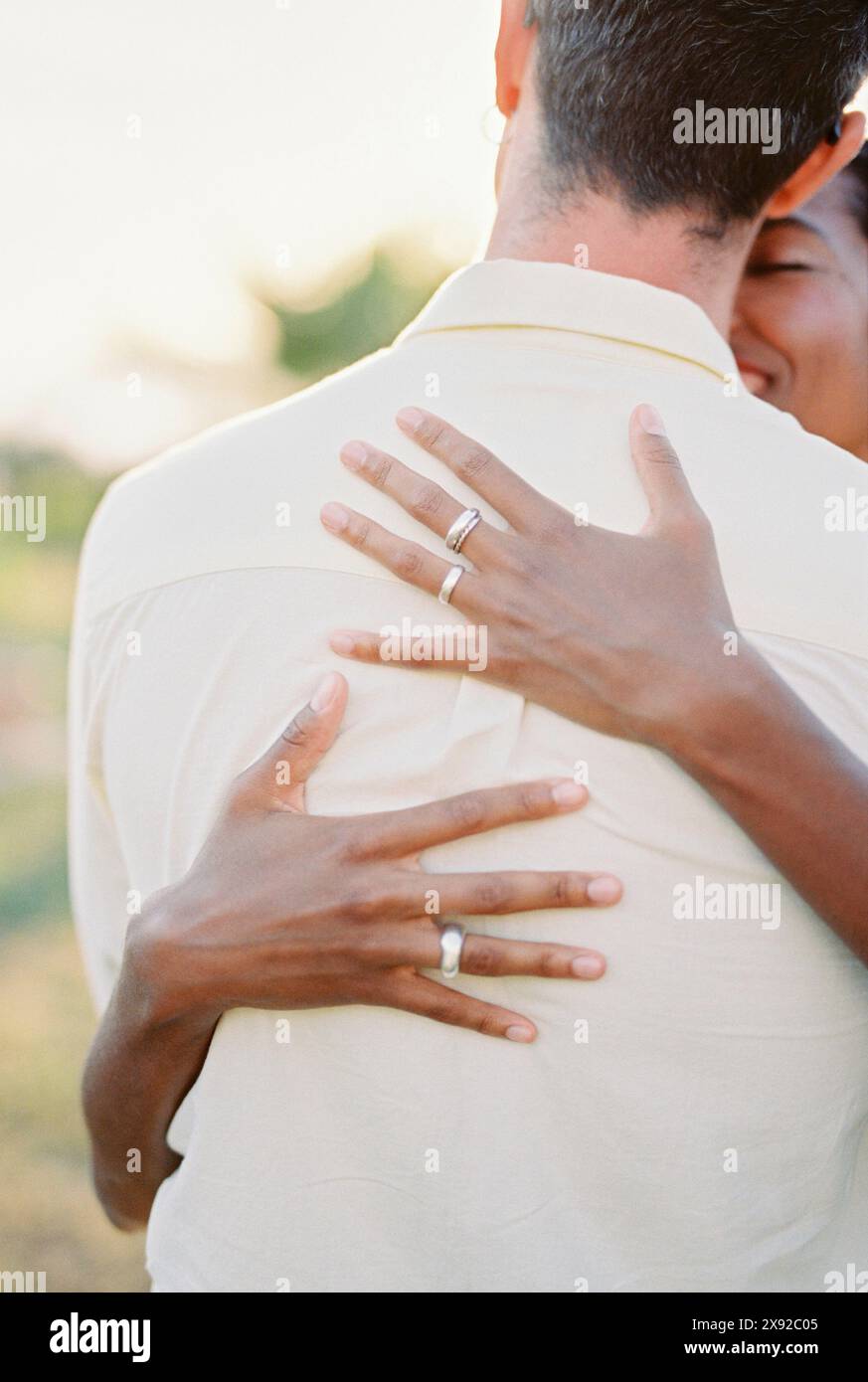 Smiling woman hugs man back, touching his neck with her nose. Back view ...