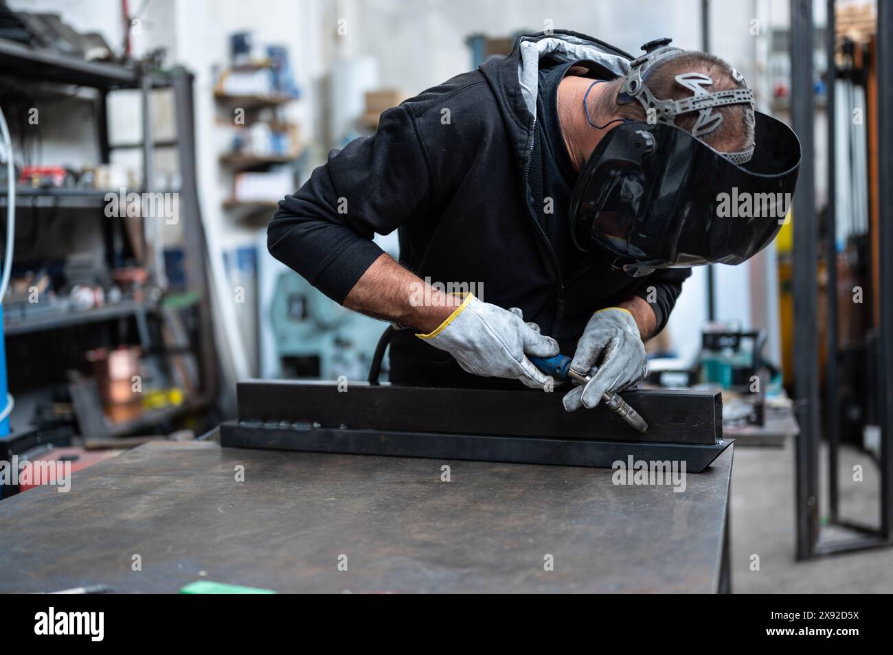Performing a weld: the man in the welding mask is positioned with the ...