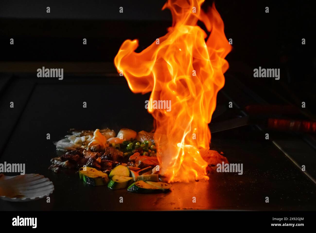chef's hands with spatula over teppanyaki. cooking vegetables meat and ...