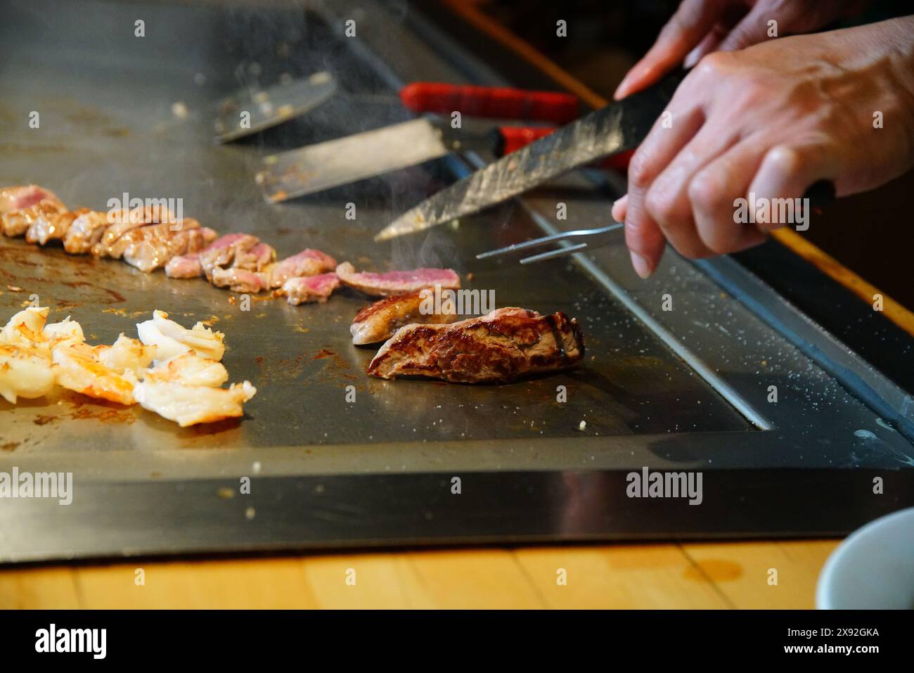 chef's hands with spatula over teppanyaki. cooking vegetables meat and ...