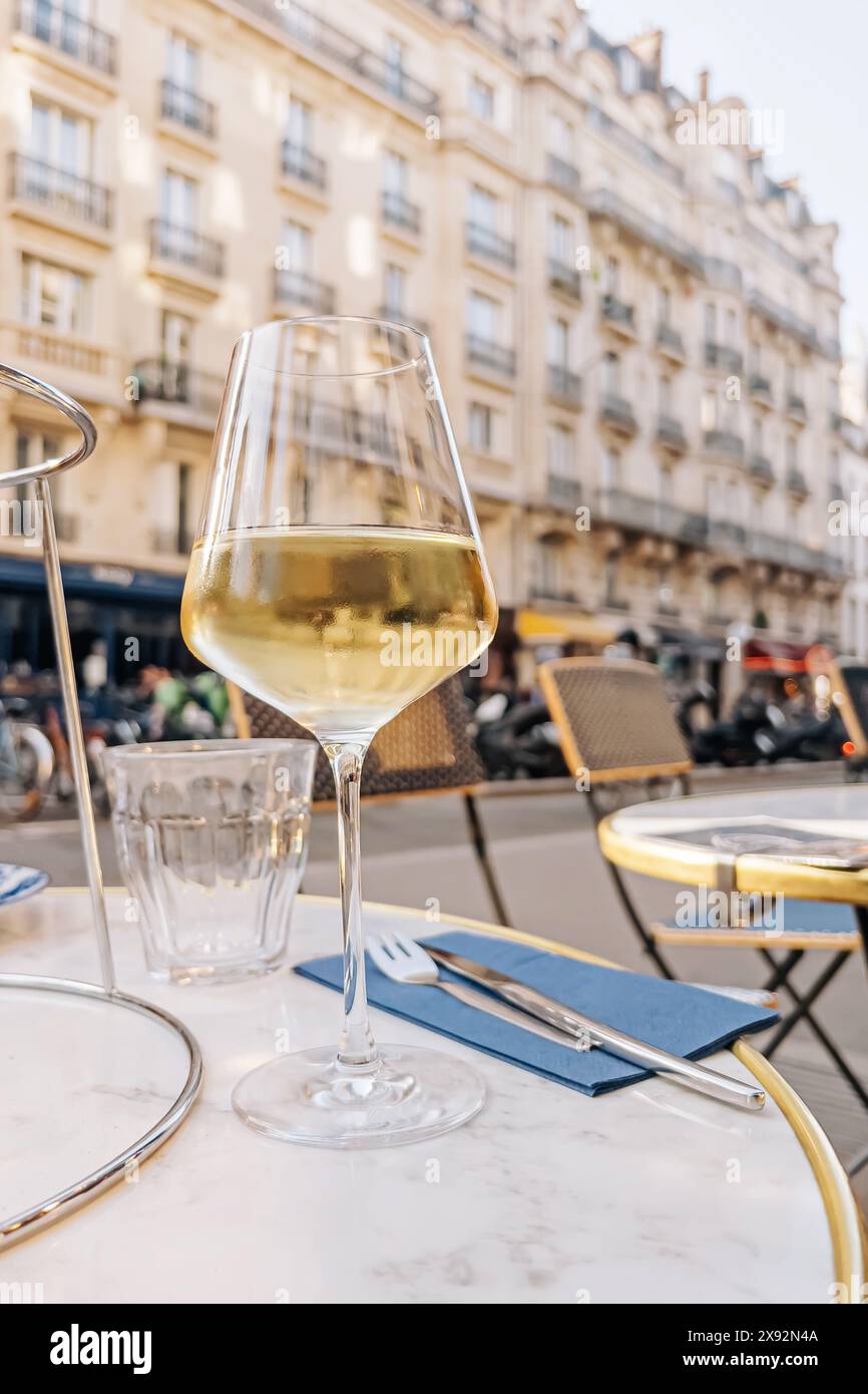 A glass of white wine standing on the table of street cafe in Paris ...