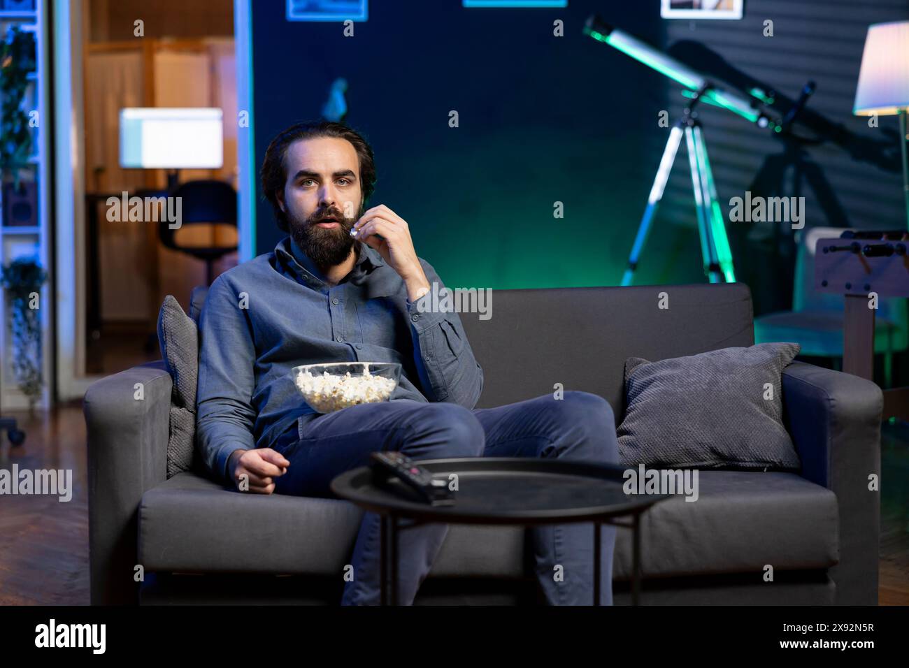 Man watching shows on TV and eating popcorn, engrossed by jaw dropping ...