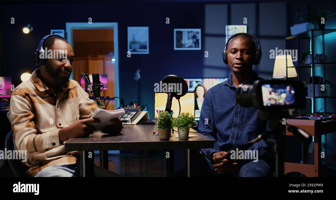 Vlogger show host interviewing guest in neon lights studio, following ...