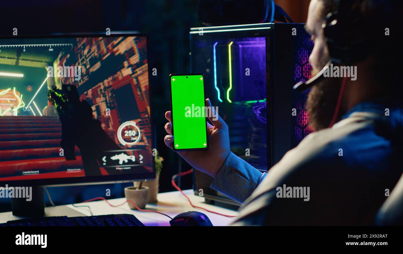 Man watching tutorial on green screen phone while playing first person ...