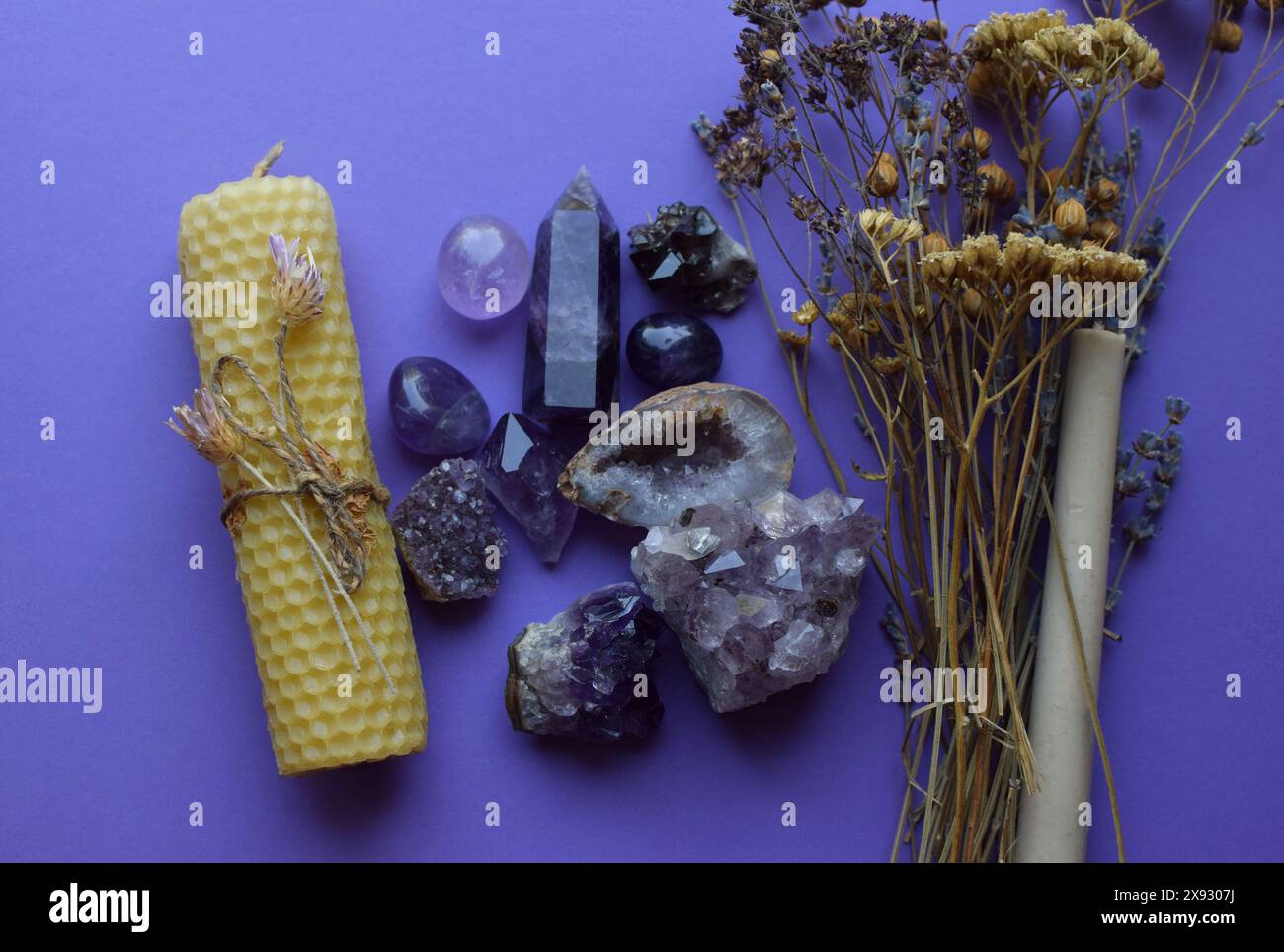 Beautiful druzy and amethyst crystals, dry herbs and wax candles on a ...