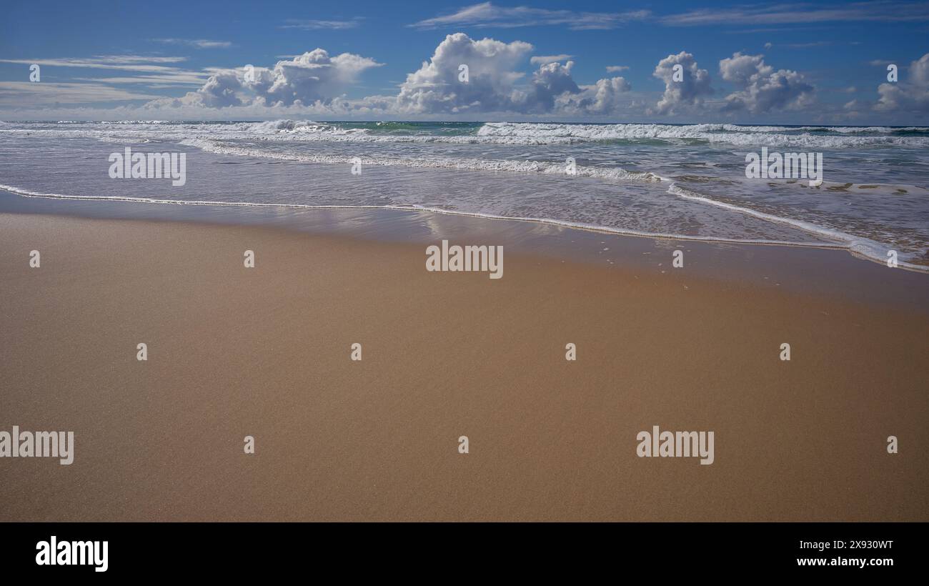 A beach scene with copy space for tourism with sand surf waves clouds ...