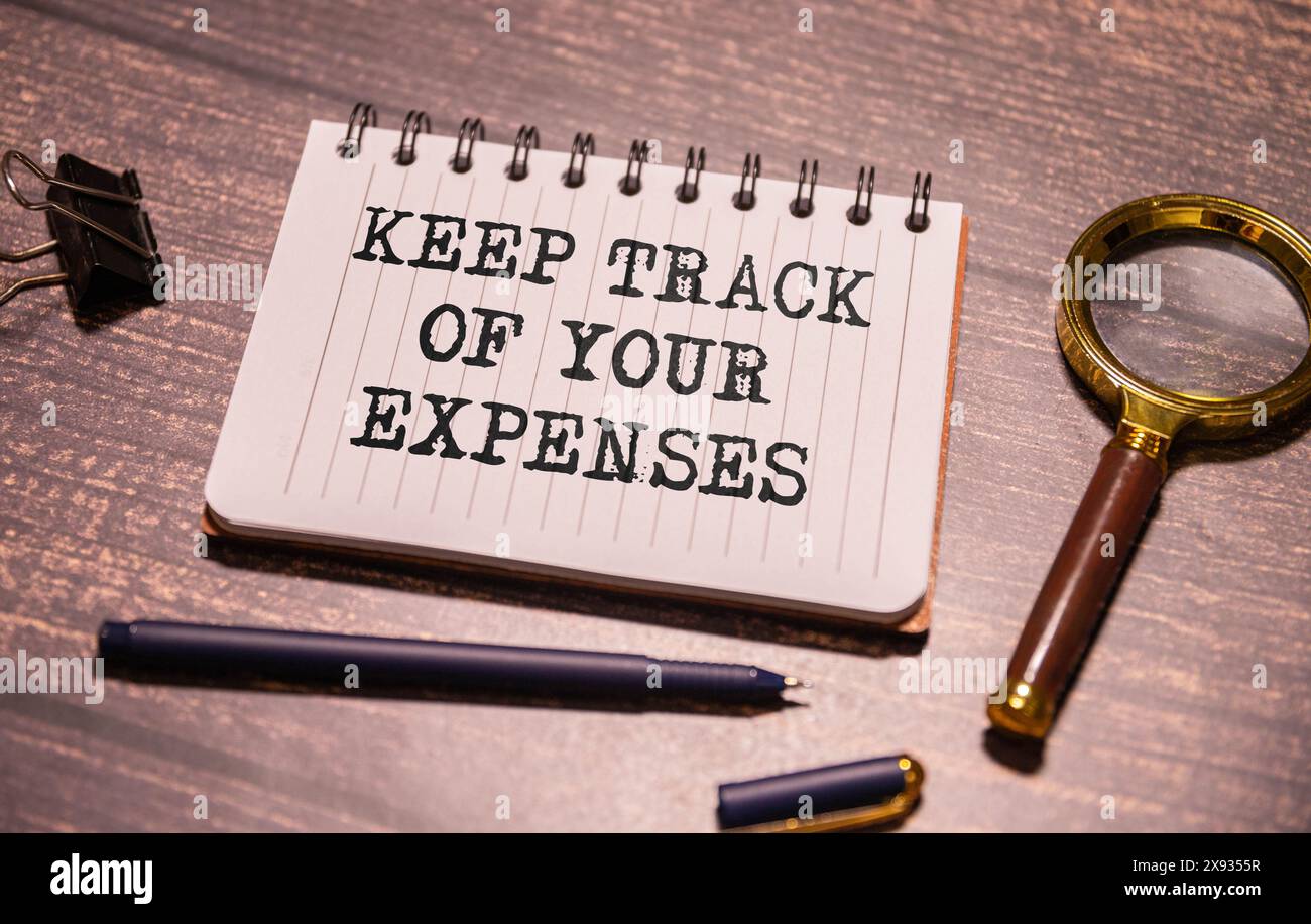 White card with the text Keep track of your expenses on wooden desk ...