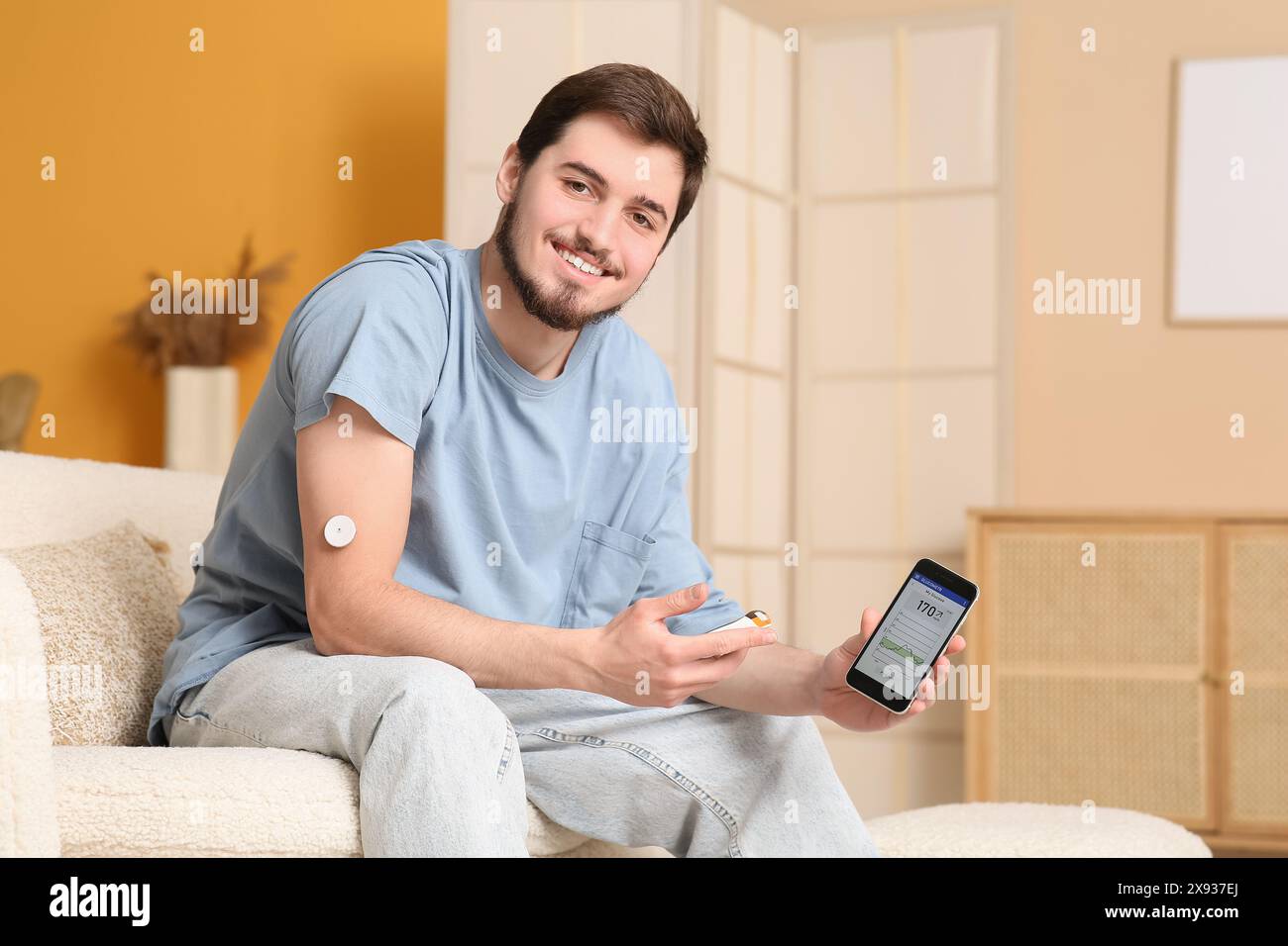 Diabetic young man with glucose sensor, glucometer and mobile phone ...