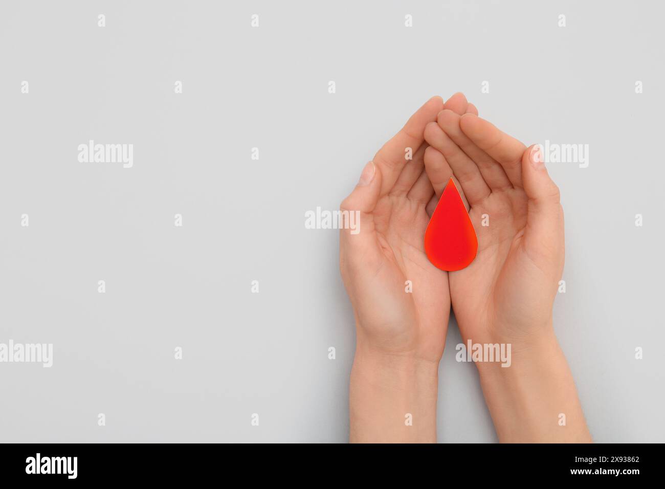 Female hands with paper blood drop on grey background. Donation blood ...