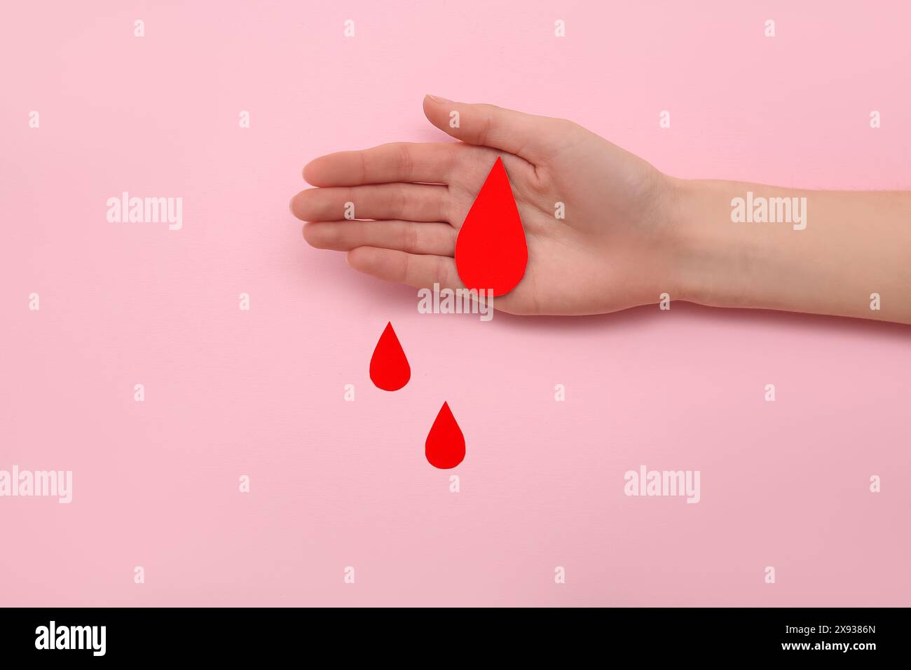 Female hand with paper blood drops on pink background. Donation blood ...