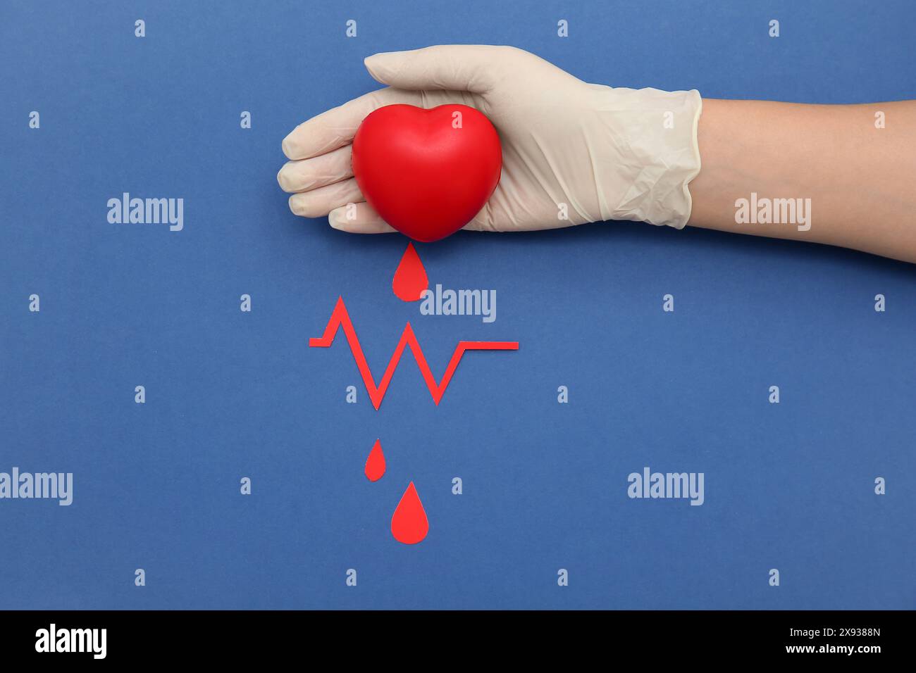 Female hand in rubber glove with grip ball, paper blood drops and ...