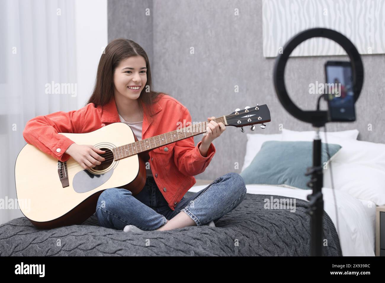 Smiling teenage blogger playing guitar while streaming at home Stock Photo - Alamy