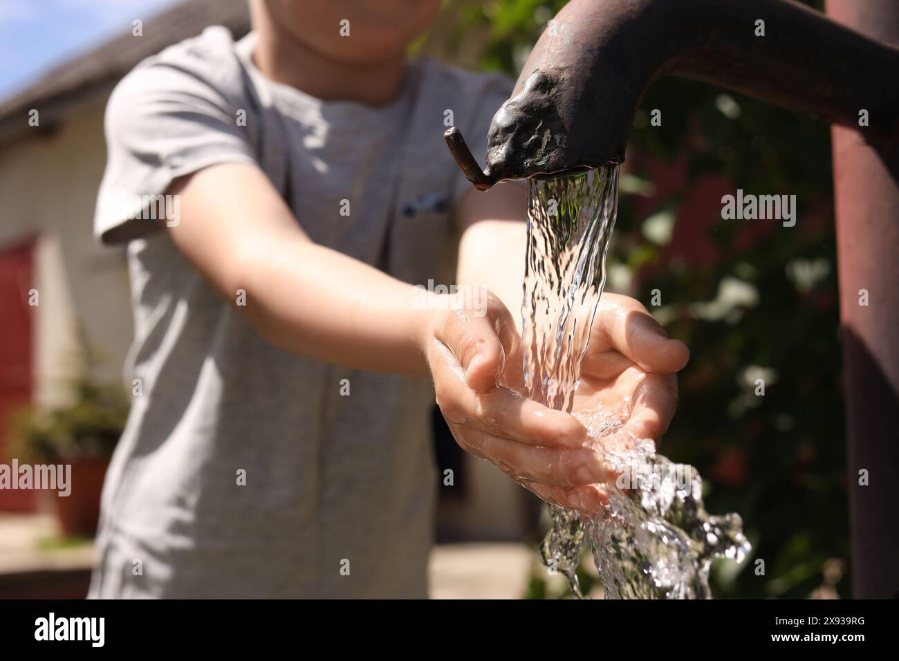 Water scarcity. Little boy drawing water with hands from tap outdoors ...