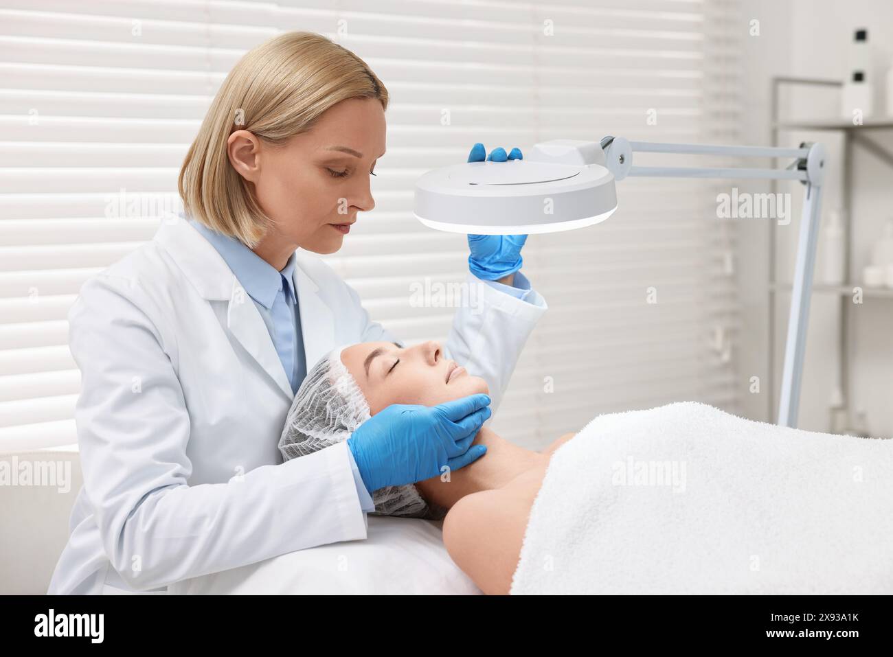 Dermatologist examining patient`s face under lamp in clinic Stock Photo ...