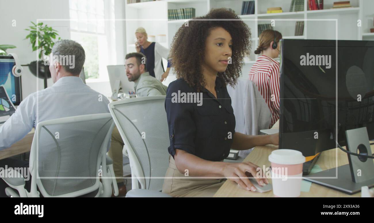 African American woman working on computer in busy office with diverse ...