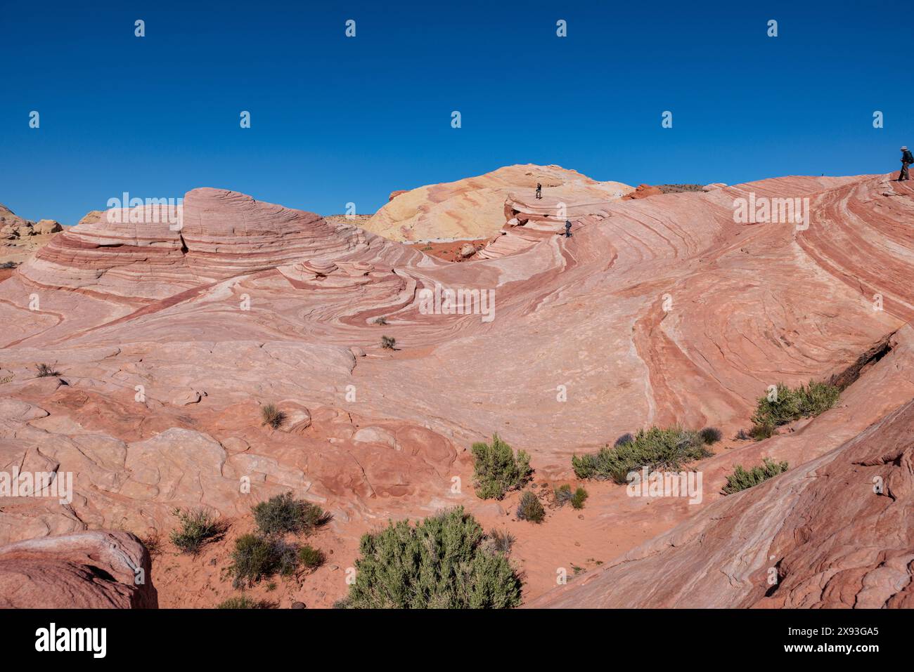 Hikers climbing on layered sandstone rock formations in the Fire Wave ...