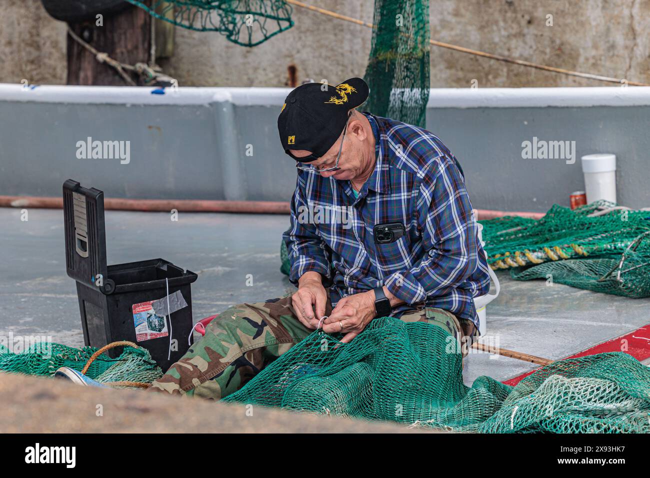 Commercial fisherman on his shrimp boat repairing his nets at the ...