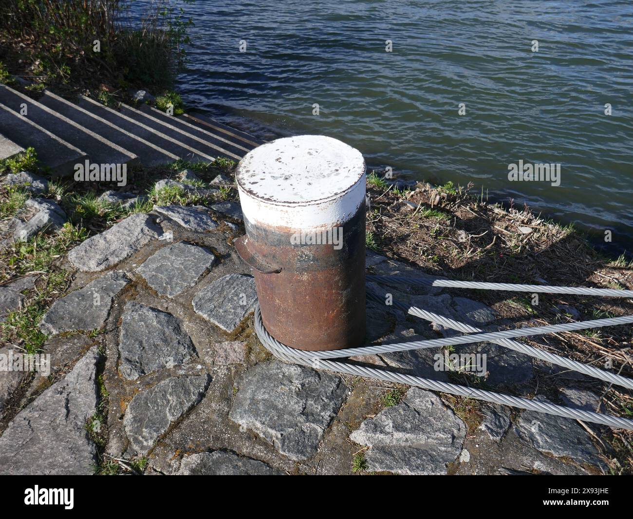 Nautical mooring bollard with lines attached near steps going into ...