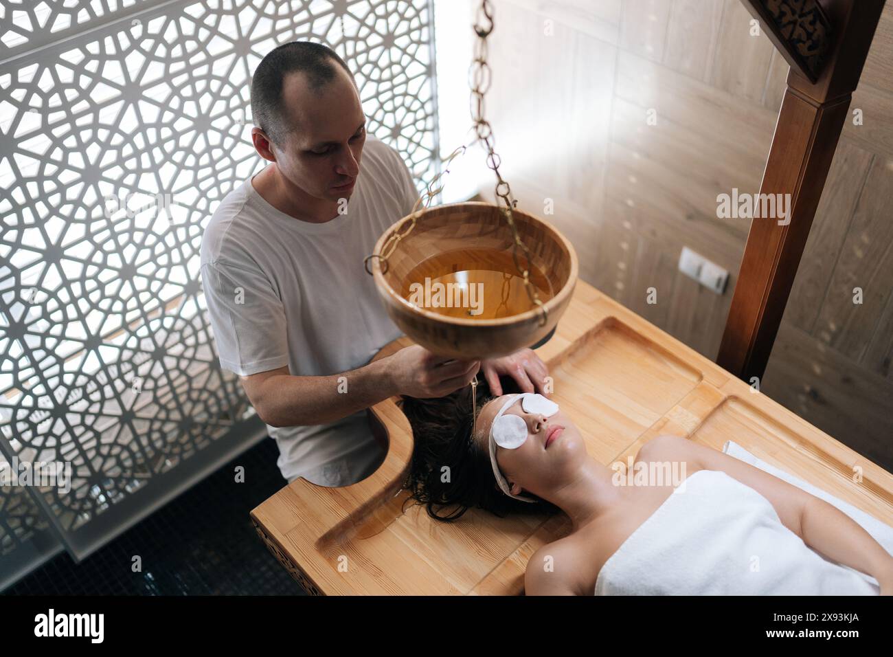 Top view of spa mater gently guiding oil stream on female client ...