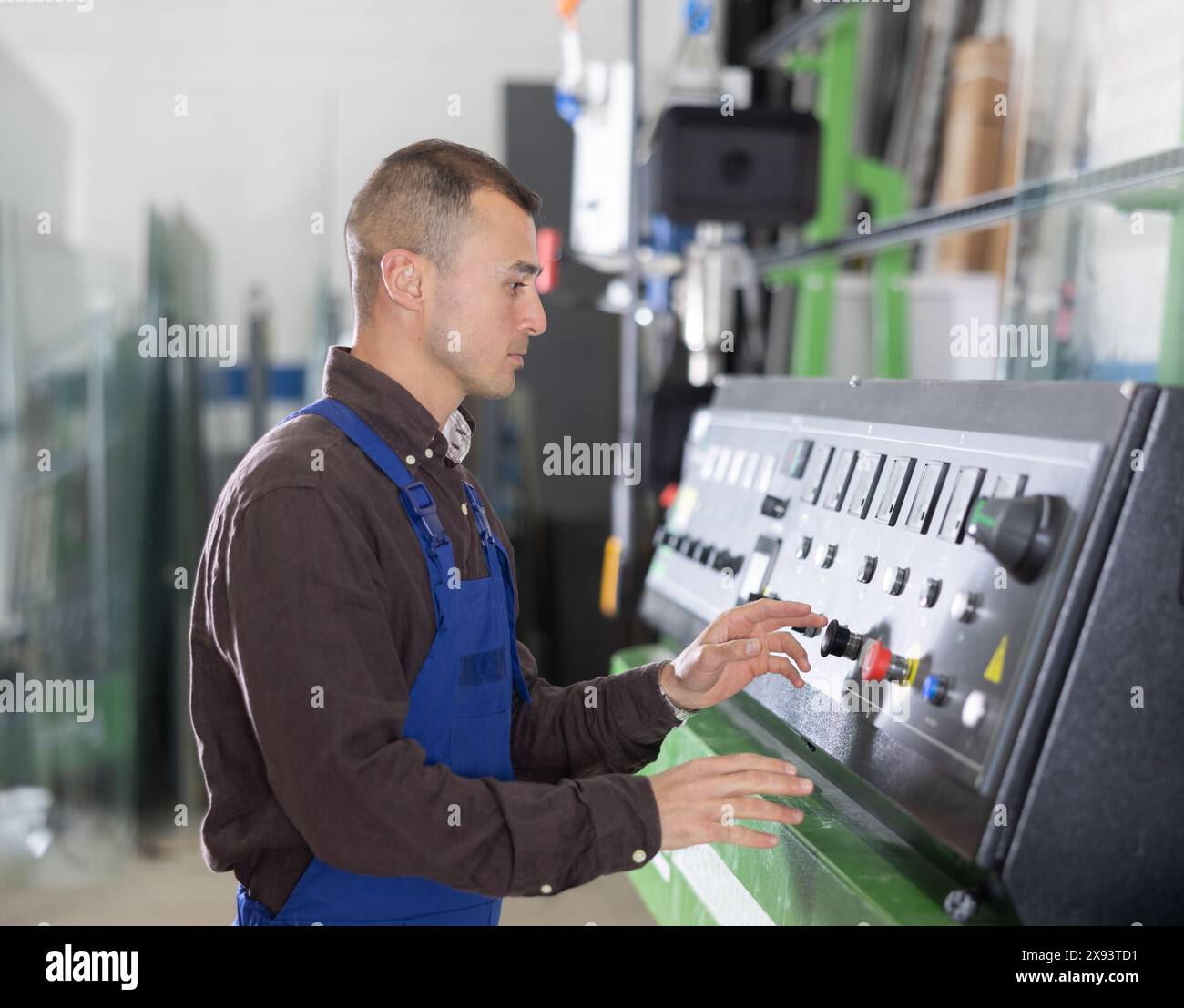 Male glass factory worker at workplace with control panel, controlling ...