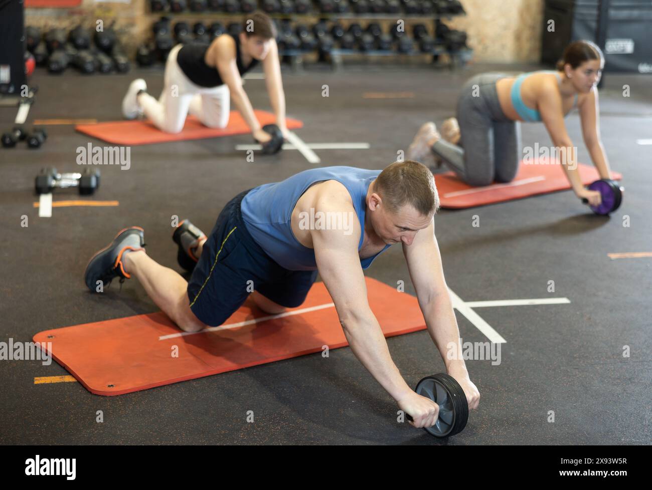 Man doing wheel rollout exercise at workout routine in gym Stock Photo ...