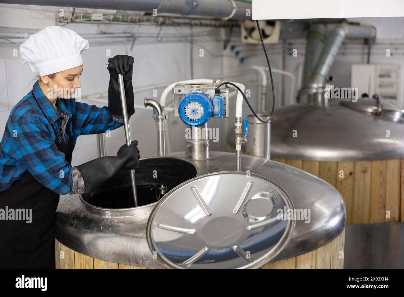 Female brewer is controls the brewing process near reservoir with beer ...