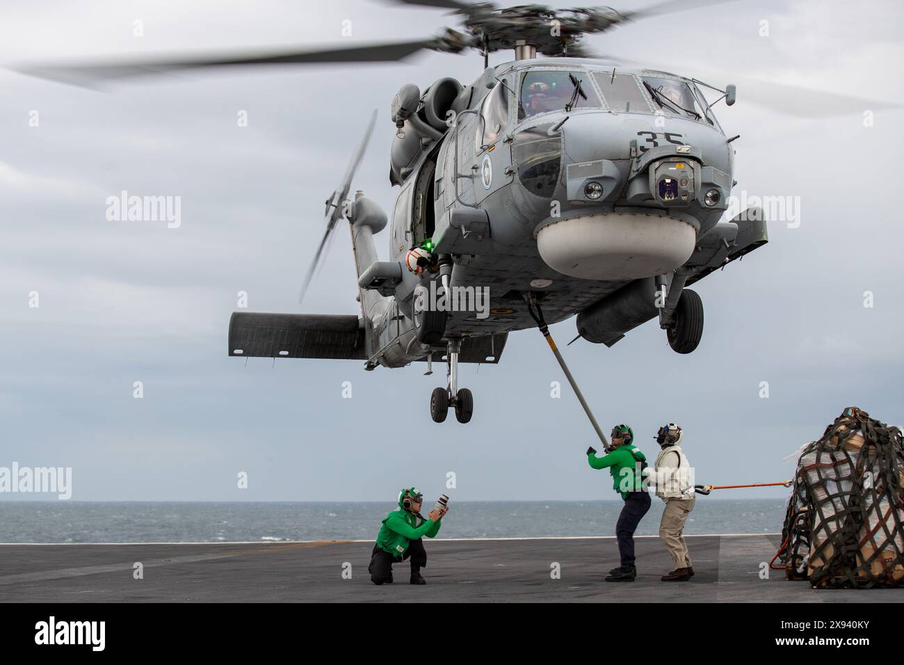 Sailors participate in a vertical replenishment on the flight deck of ...