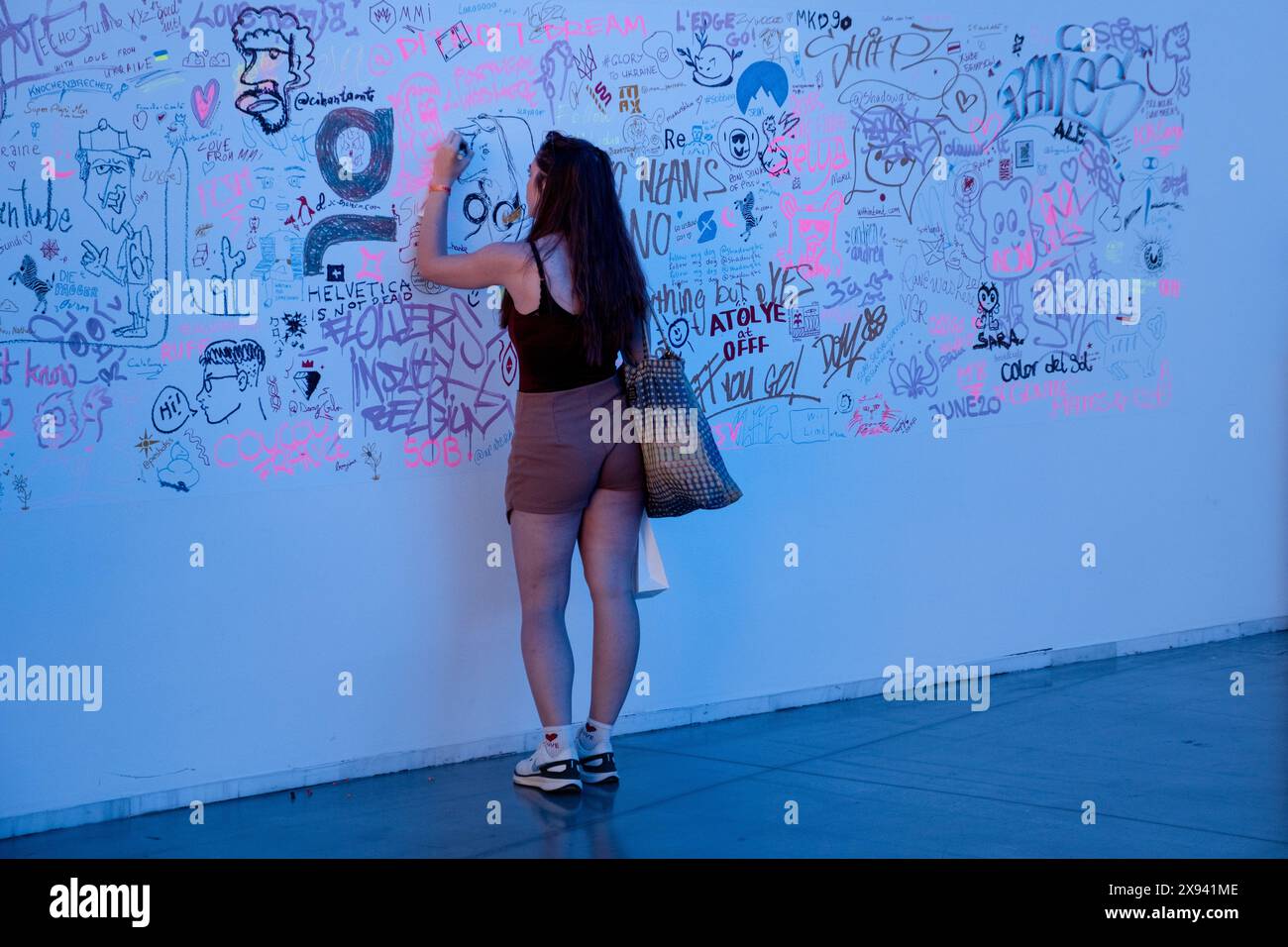 A woman artist adds her contribution to the wall of graffiti at OFFF ...