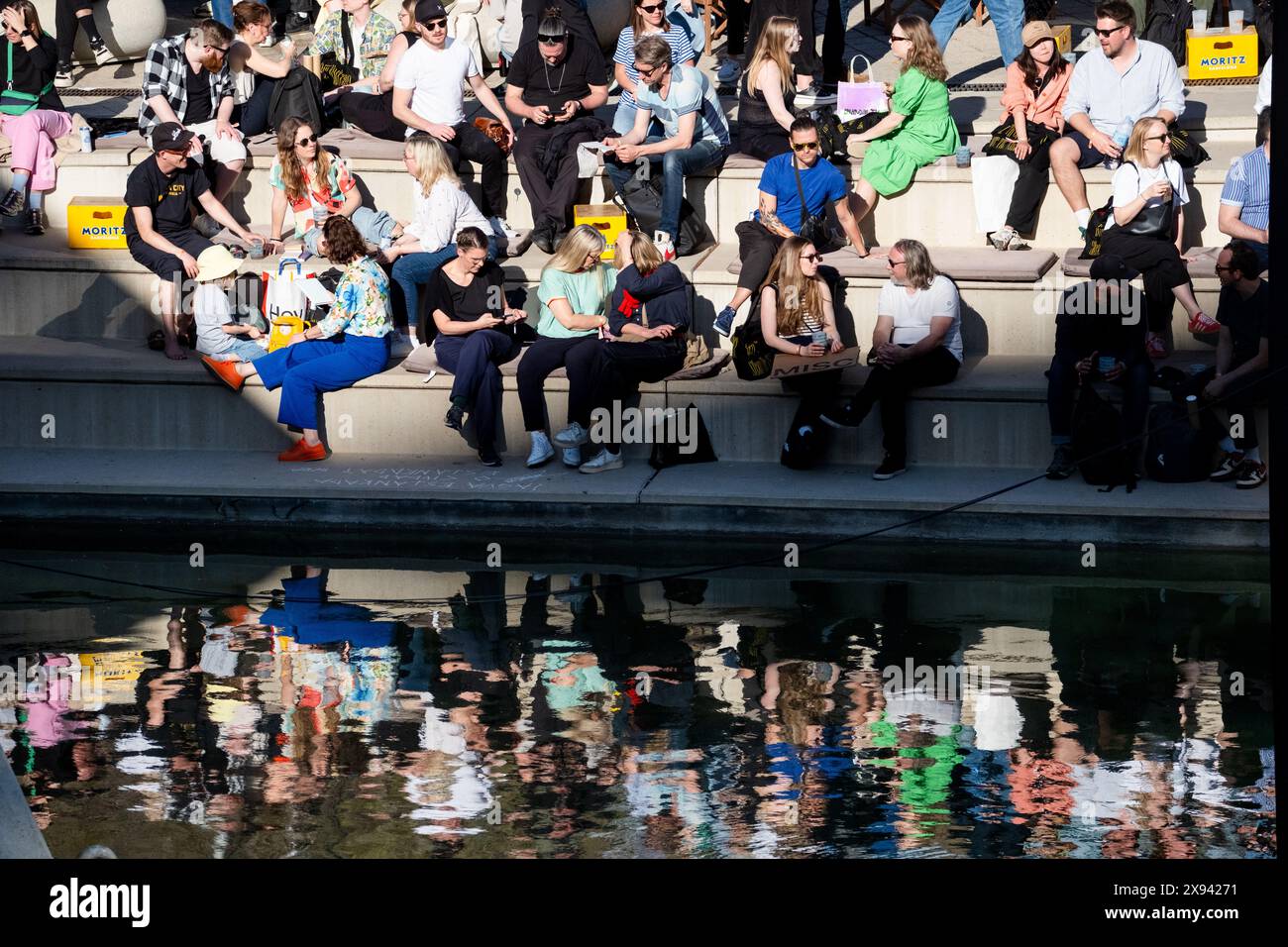 Attendees sit by the moat water feature to chill out and mingle between ...