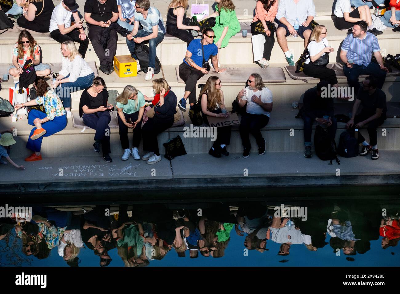 Attendees sit by the moat water feature to chill out and mingle between ...