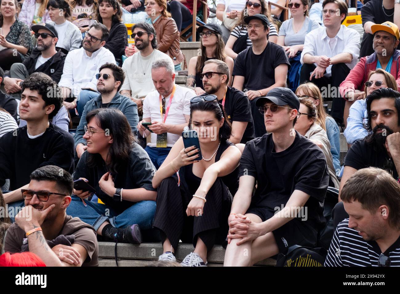 Attendees sat outside in the sunshine watch talks from the Open Room ...
