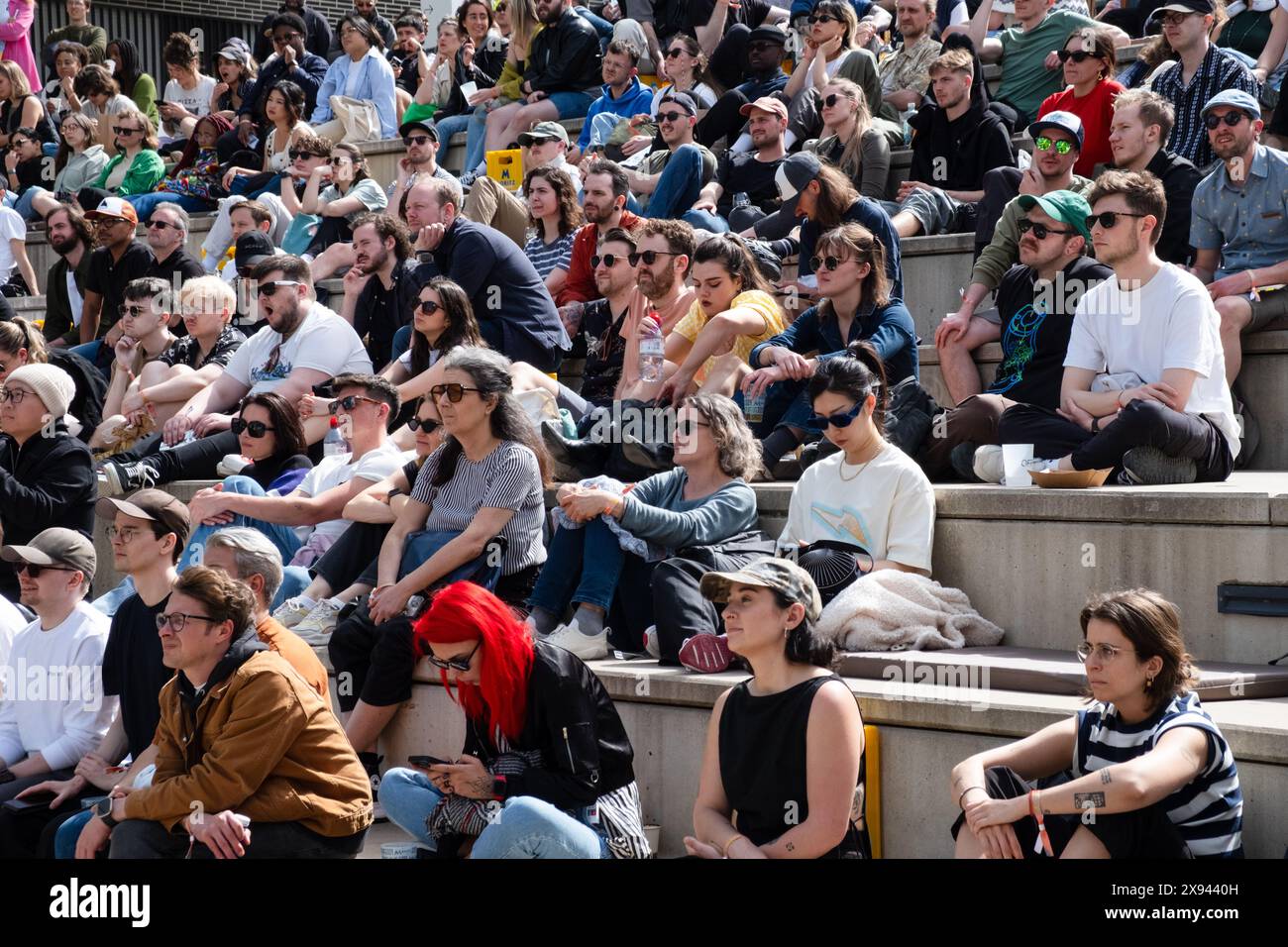 Attendees sat outside in the sunshine watch talks from the Open Room ...