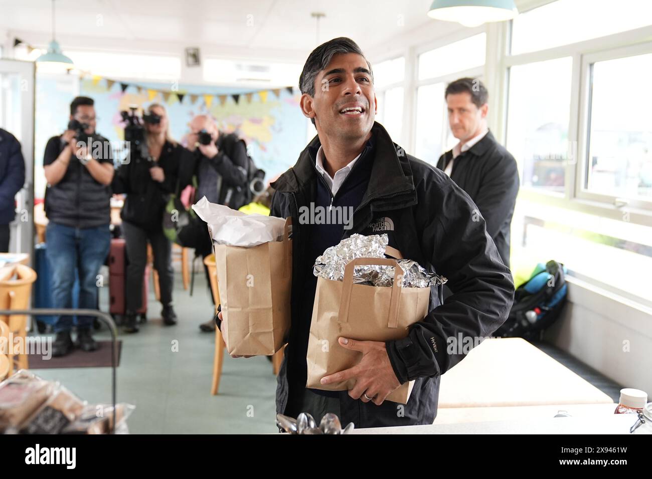 Prime Minister Rishi Sunak speaks with a cafe worker as he picks up ...