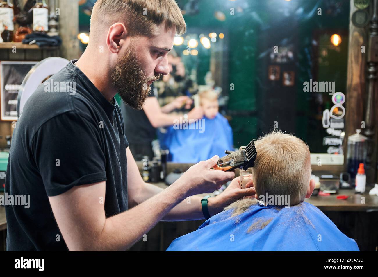 Professional barber concentrated on his work. Little kid getting first ...