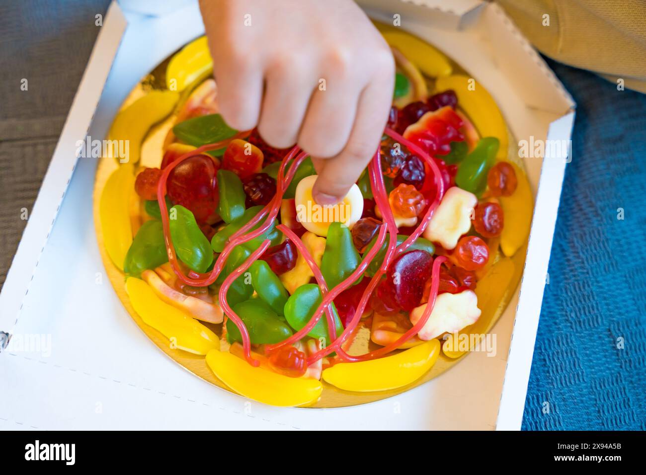 Child's hand takes Swedish gummy candies: candy pizza in box. Kid core ...