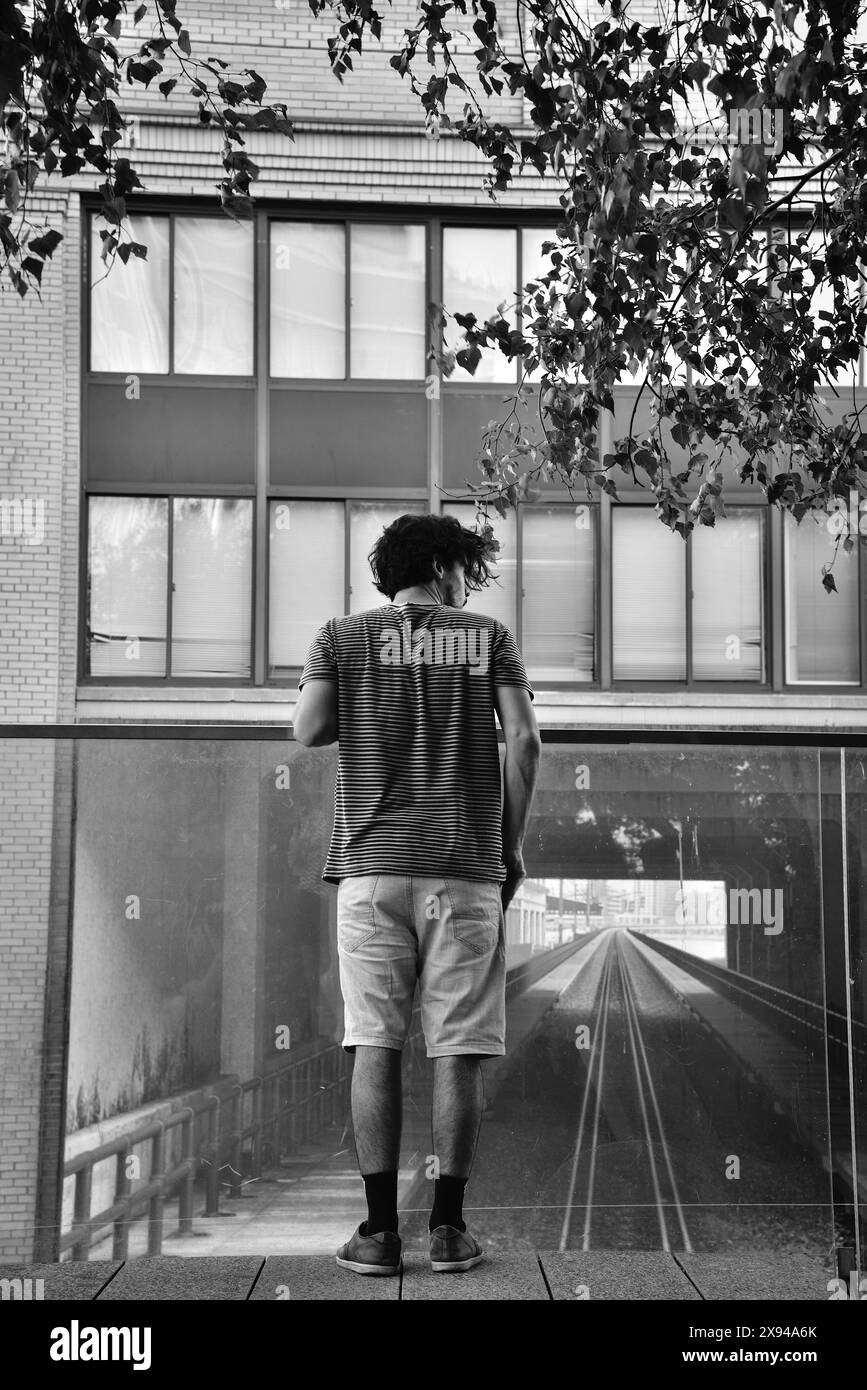 A Young Man standing on High Line Park, NYC, looking out over a Glass ...