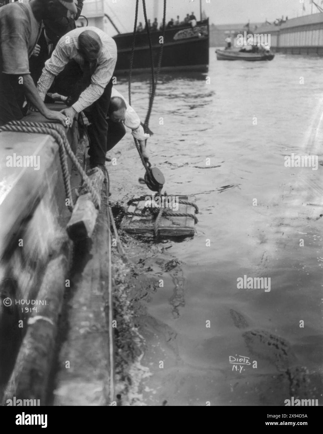 Houdini in action, in a packing case, is lowered into New York Bay ...