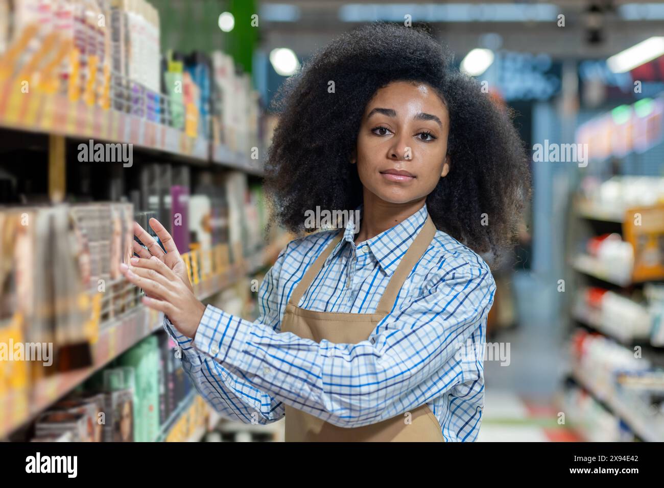 Female store employee wearing an apron organizing products on a ...
