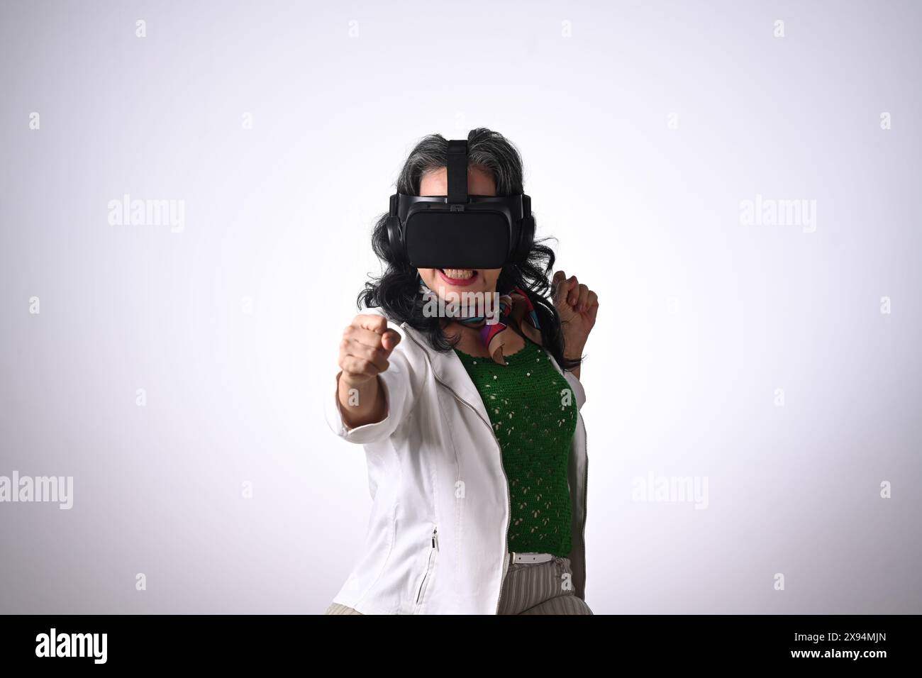 Joyful senior woman in boxing stance, playing action simulator game in ...