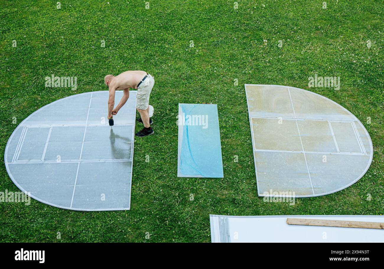 Man assemble domestic greenhouse kit at home. Pieces lay around on home ...