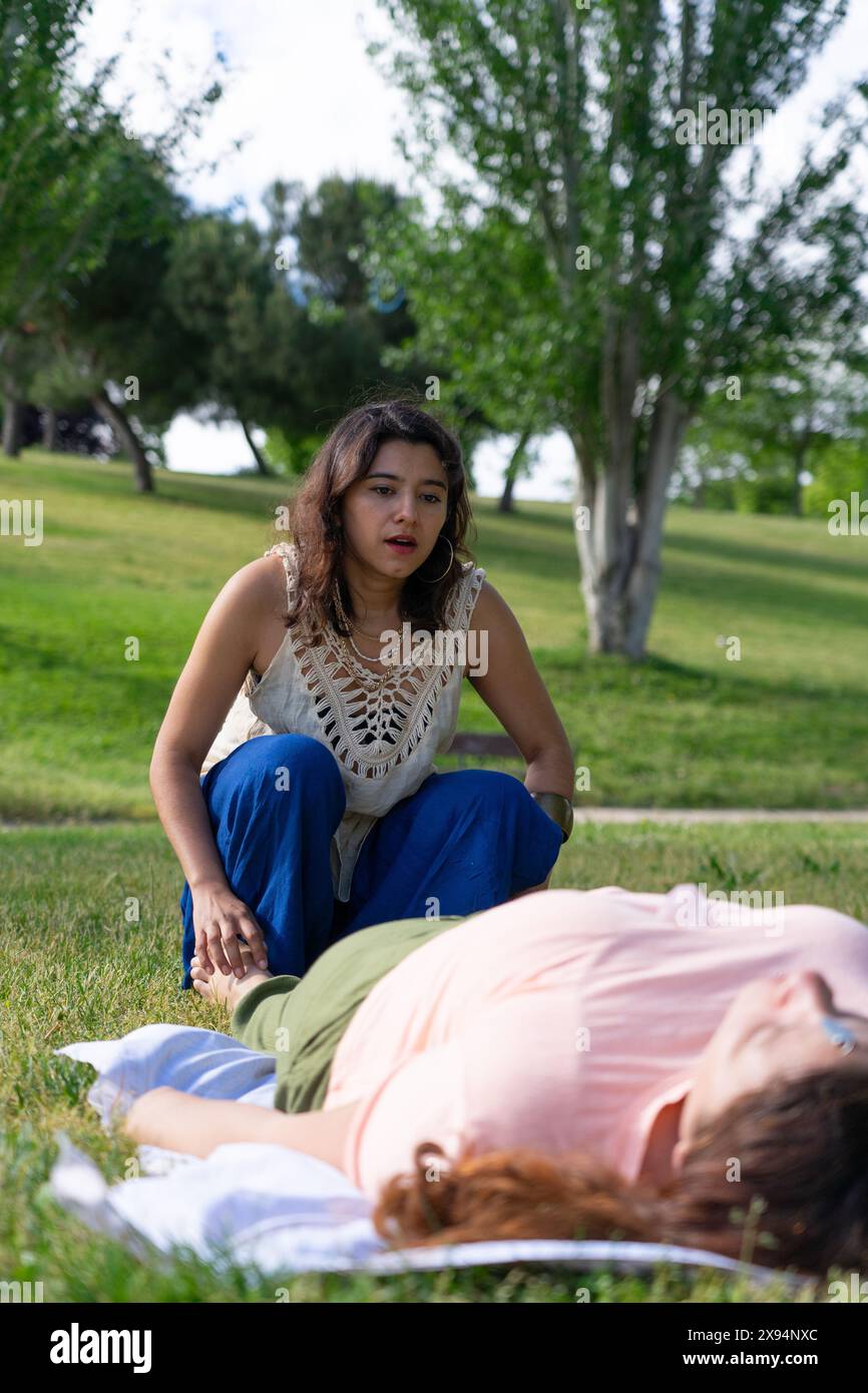 Latin woman doing conscious breathing therapy to a woman in nature ...