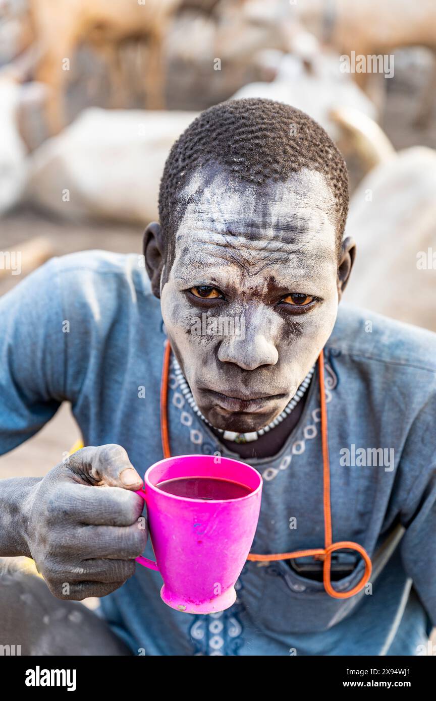 Dust covered man drinking local coffee, Mundari tribe, South Sudan ...