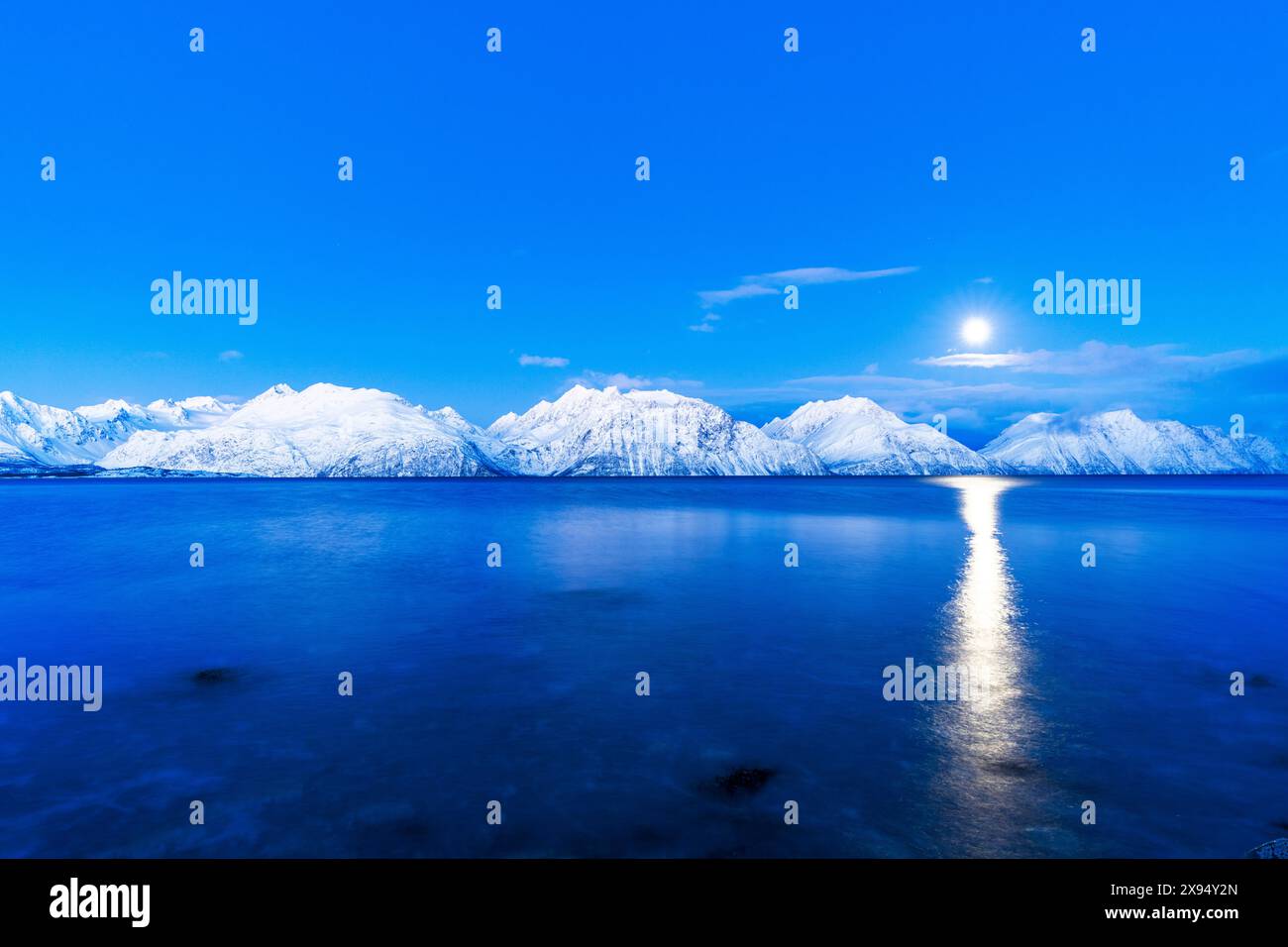 Full moon above snowy peaks in the Arctic landscape reflecting in the ...