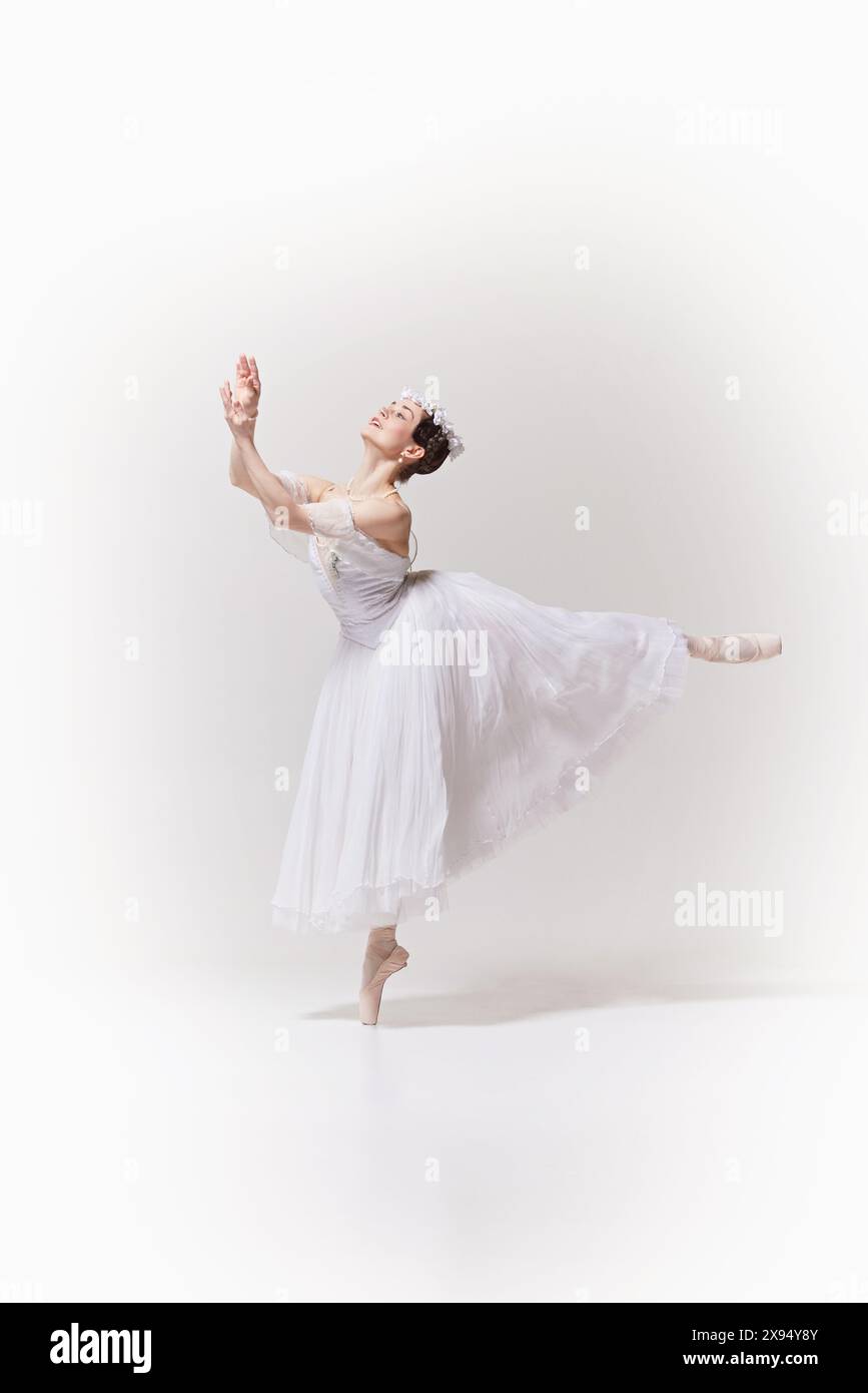 Charming young ballerina dancer balancing on pointe and reaching to ...